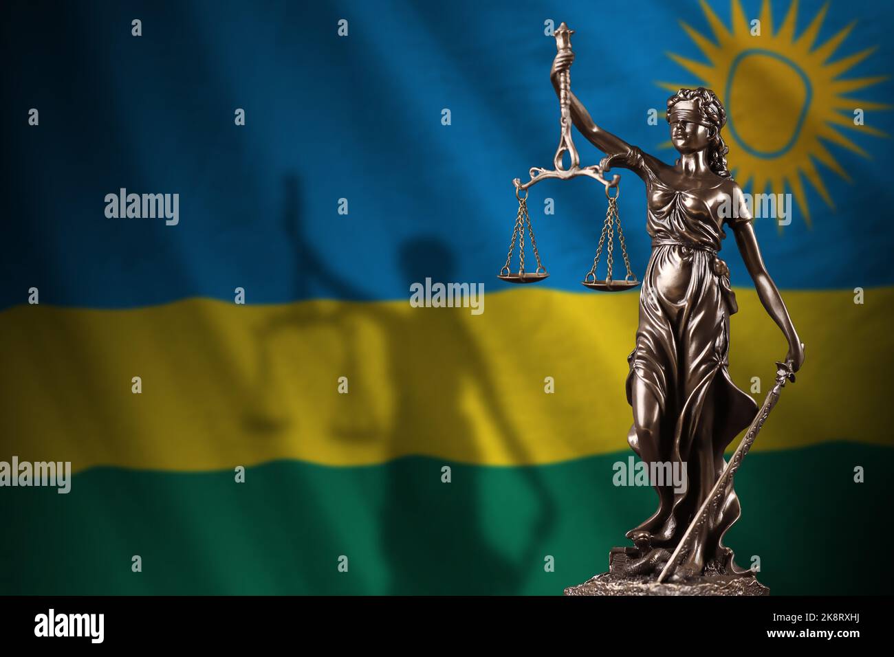 Rwanda flag with statue of lady justice and judicial scales in dark room. Concept of judgement ...