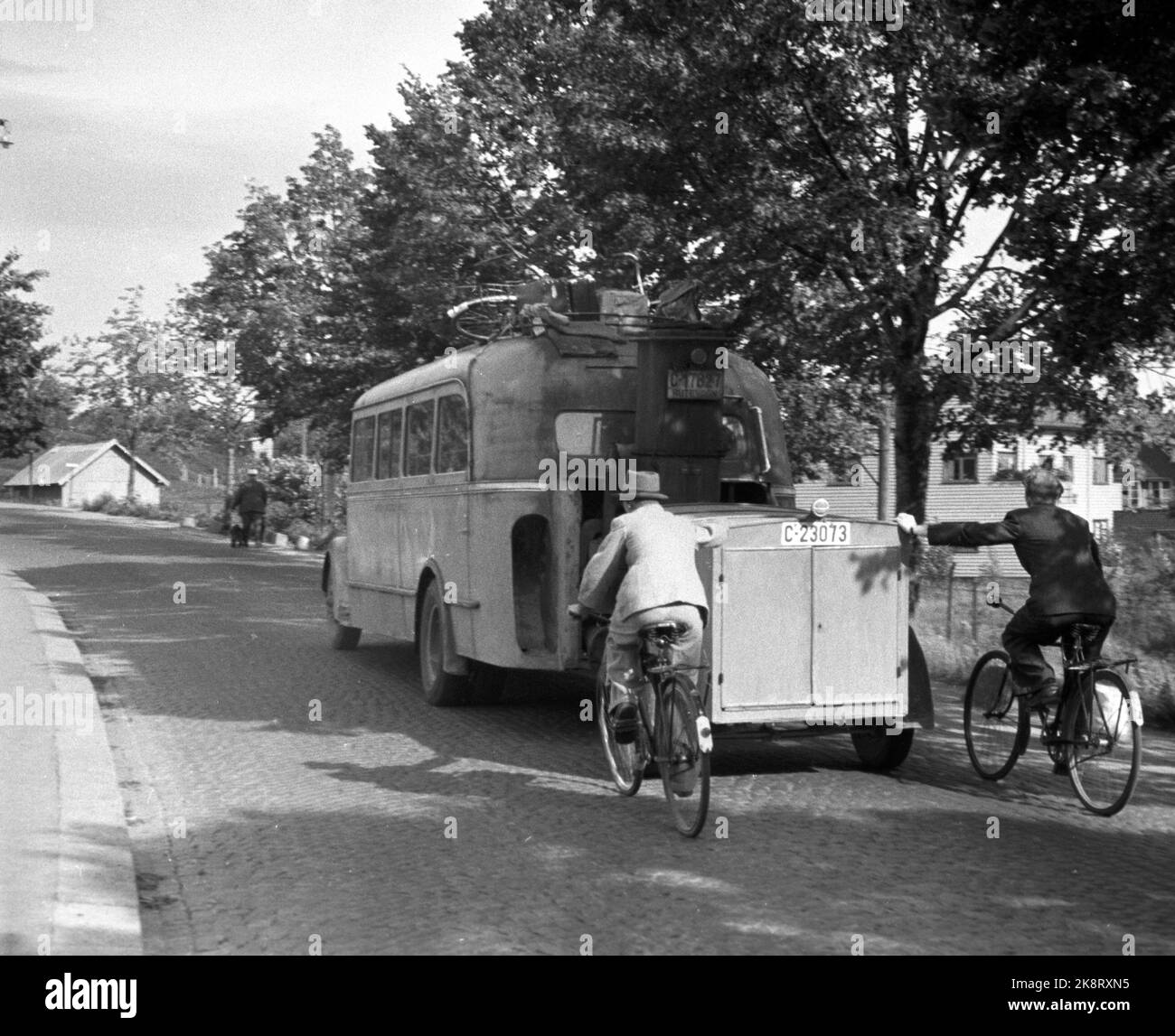 WW2 Oslo 19440816 Two cyclists hang on a bus. The bus is rigged for ...