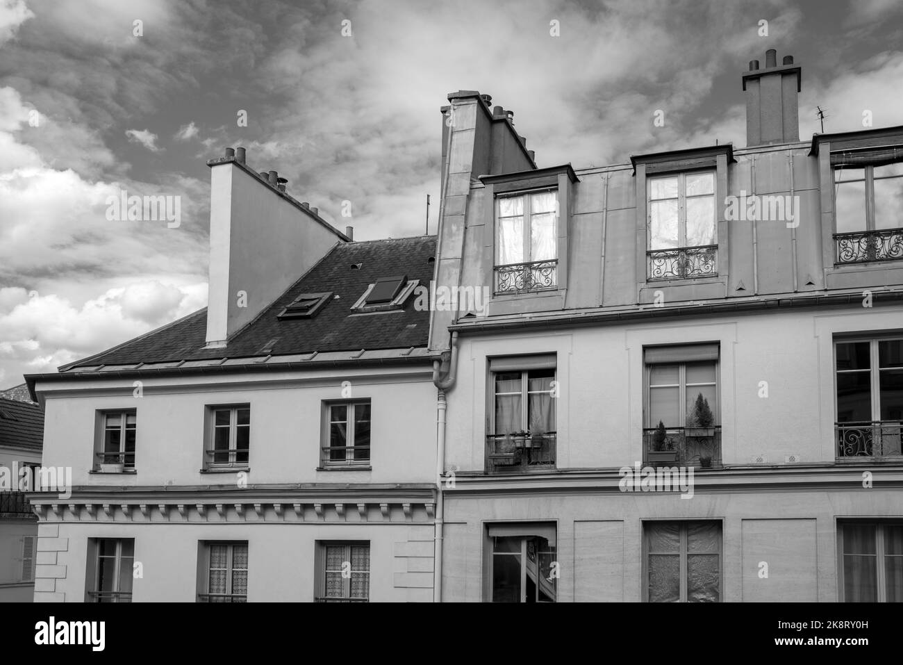 A low-angle grayscale of a France home facade, gloomy, cloudy sky ...