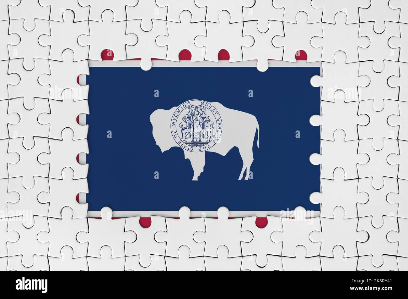 Wyoming US state flag in frame of white puzzle pieces with missing ...