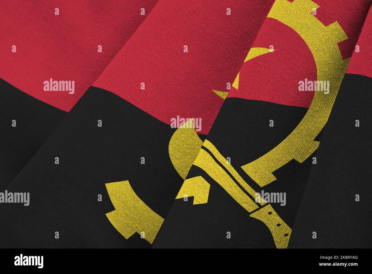 Angola flag with big folds waving close up under the studio light ...