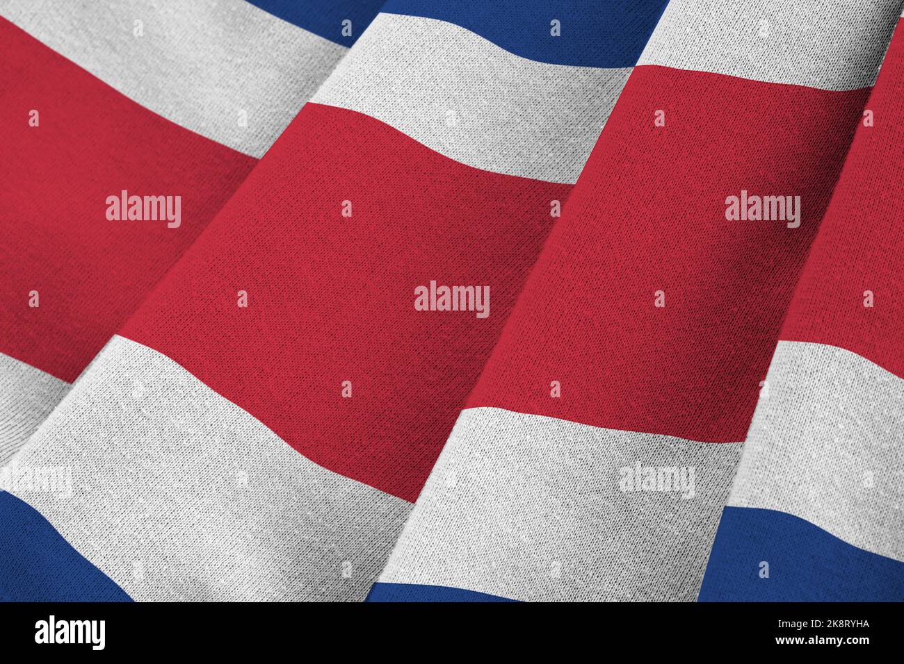 Costa Rica flag with big folds waving close up under the studio light ...