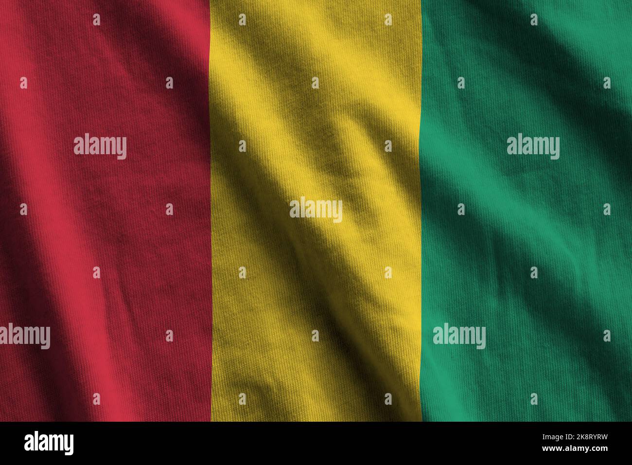 Guinea flag with big folds waving close up under the studio light ...