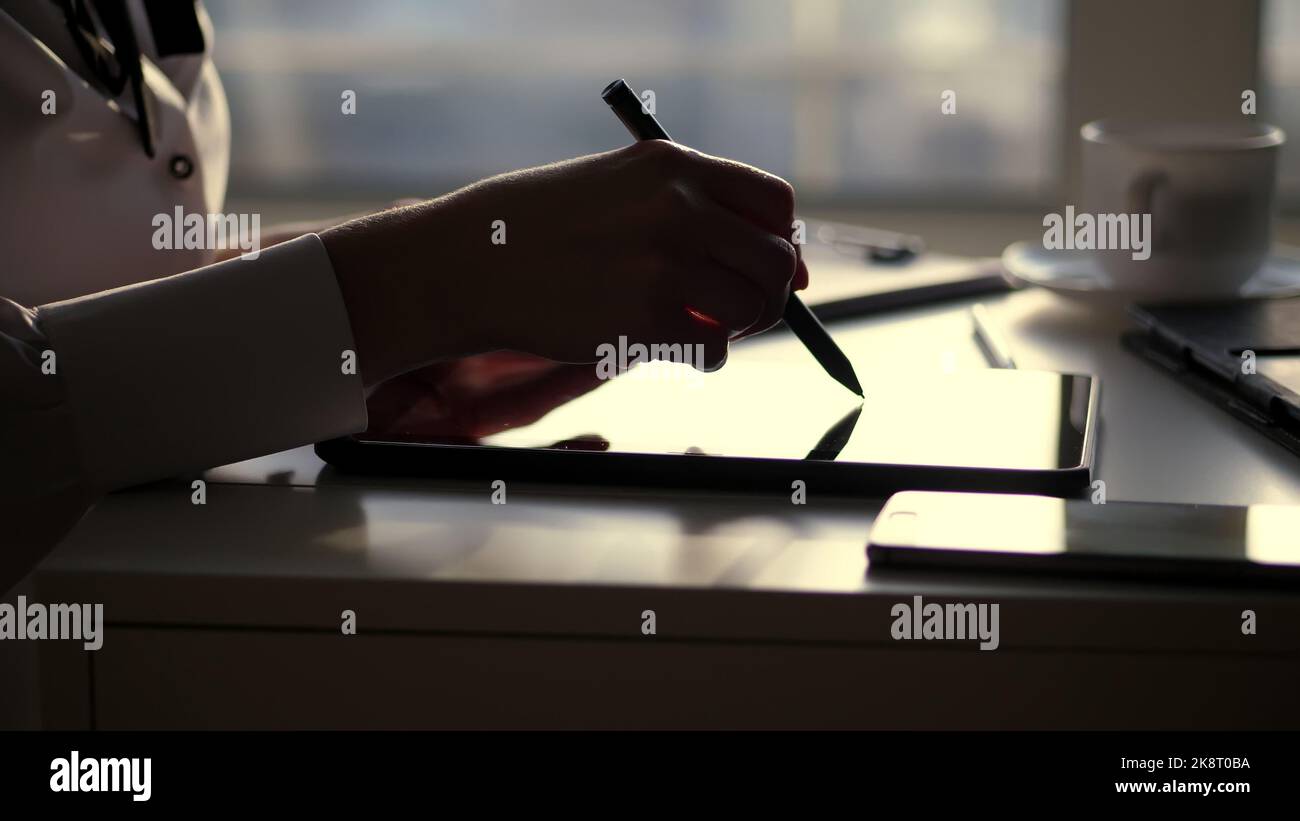 dark silhouette of businesswoman, closeup of hands. she writes ...