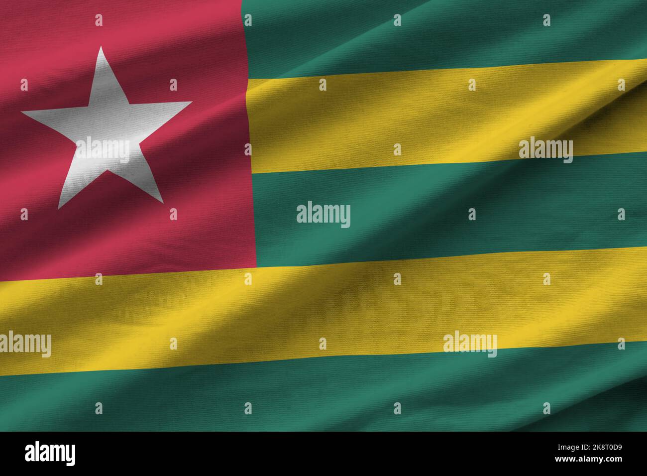 Togo flag with big folds waving close up under the studio light indoors ...