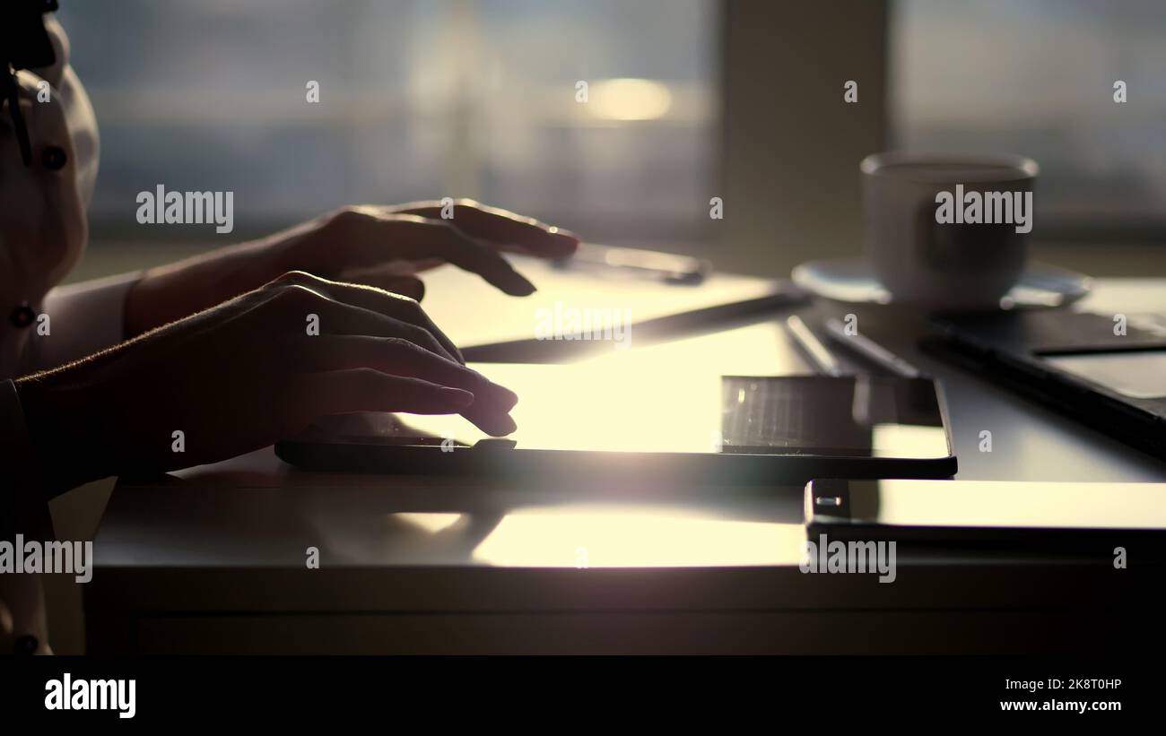 closeup, dark silhouette of female hands. she is typing something in ...