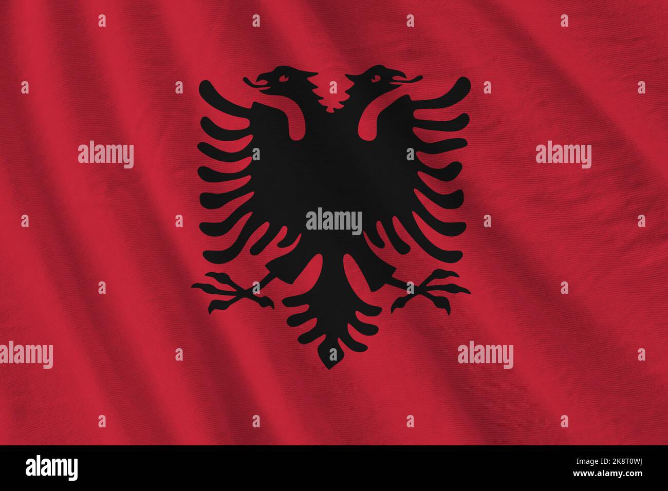 Albania flag with big folds waving close up under the studio light ...