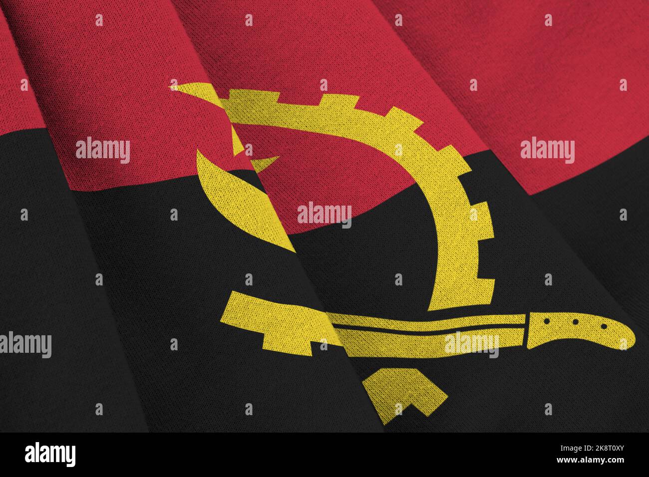 Angola flag with big folds waving close up under the studio light ...