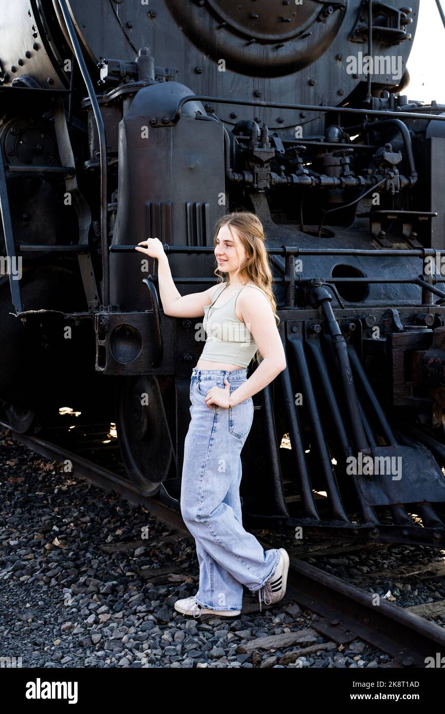 Teenage Girl in Trainyard Standing in Front of Old Black Steam Engine ...