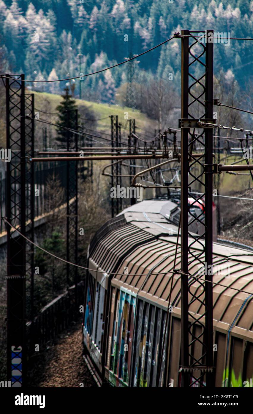 A vertical shot of a freight train on tracks with metal poles near ...