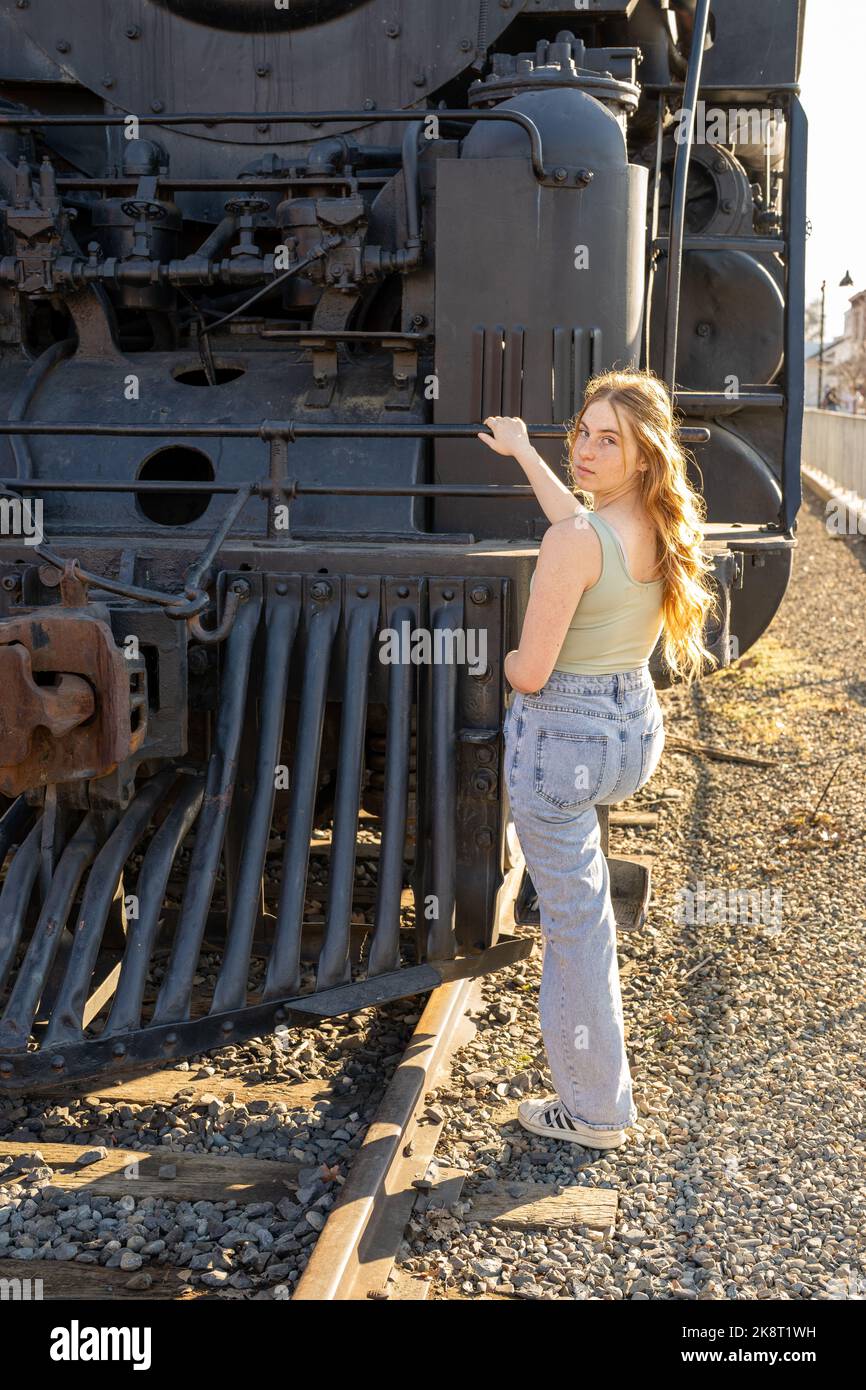 Teenage Girl in Trainyard Standing in Front of Old Black Steam Engine ...