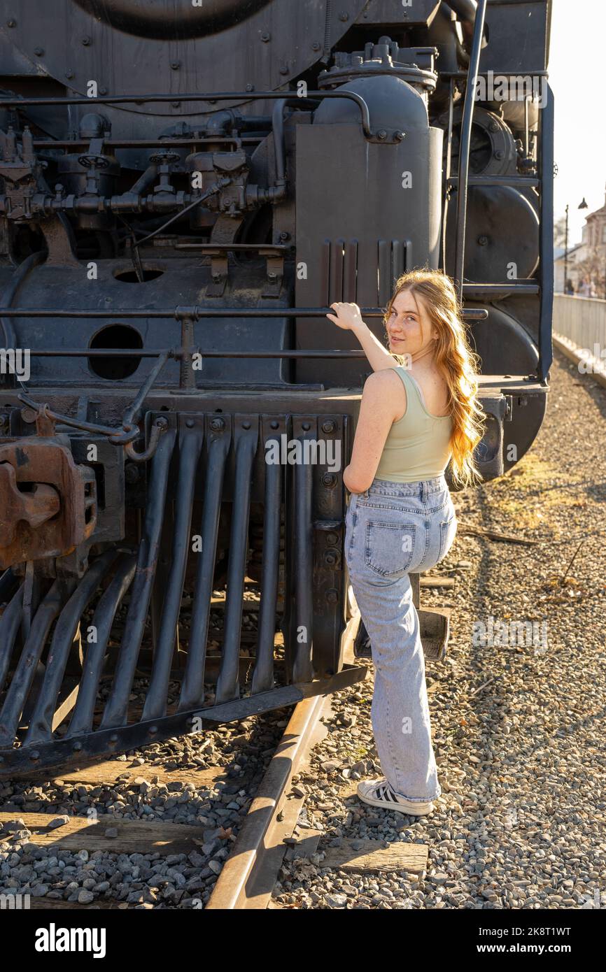 Teenage Girl in Trainyard Standing in Front of Old Black Steam Engine ...