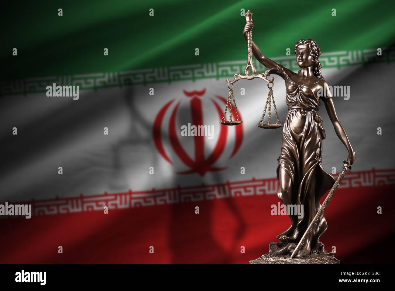 Iran flag with statue of lady justice and judicial scales in dark room ...