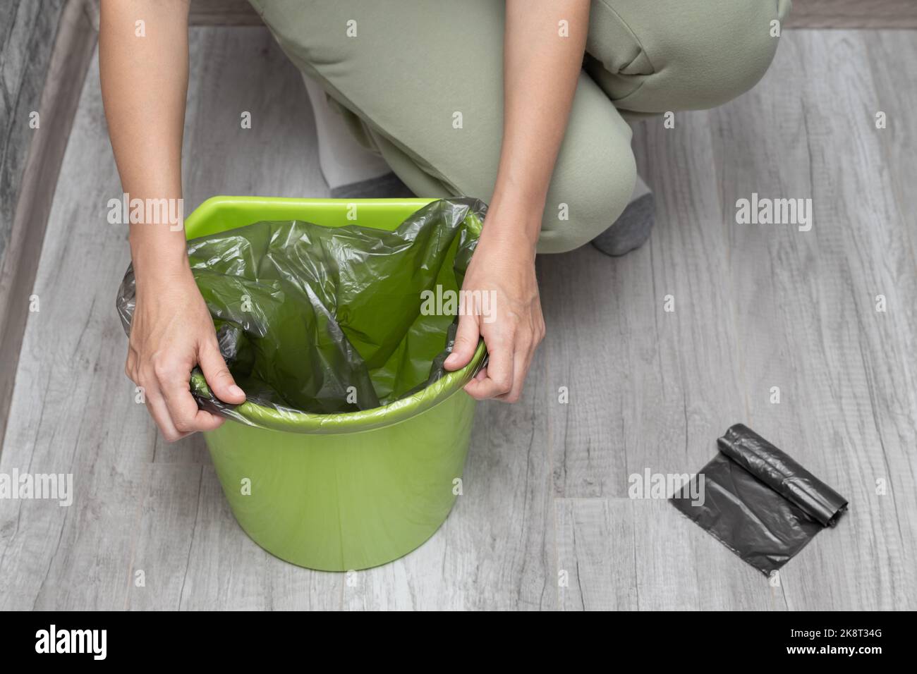 a woman changes a garbage bag in a bucket. man tearing off a trash bag ...