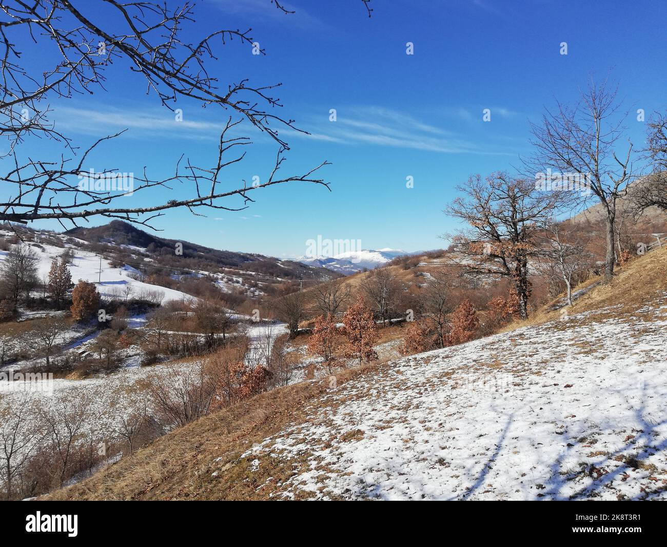 An aerial view of snow covered mountain landscape surrounded by trees ...