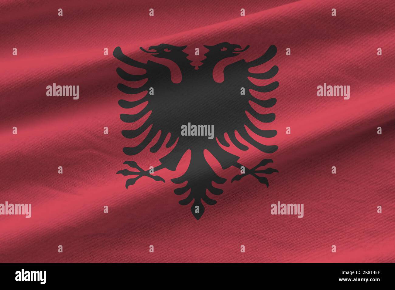 Albania flag with big folds waving close up under the studio light ...