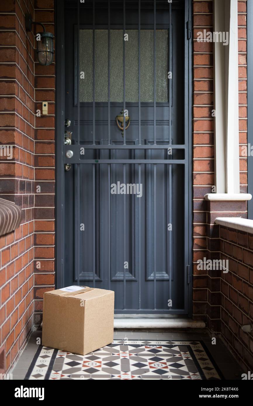 A vertical shot of a box put in front of a black door with metal bars ...