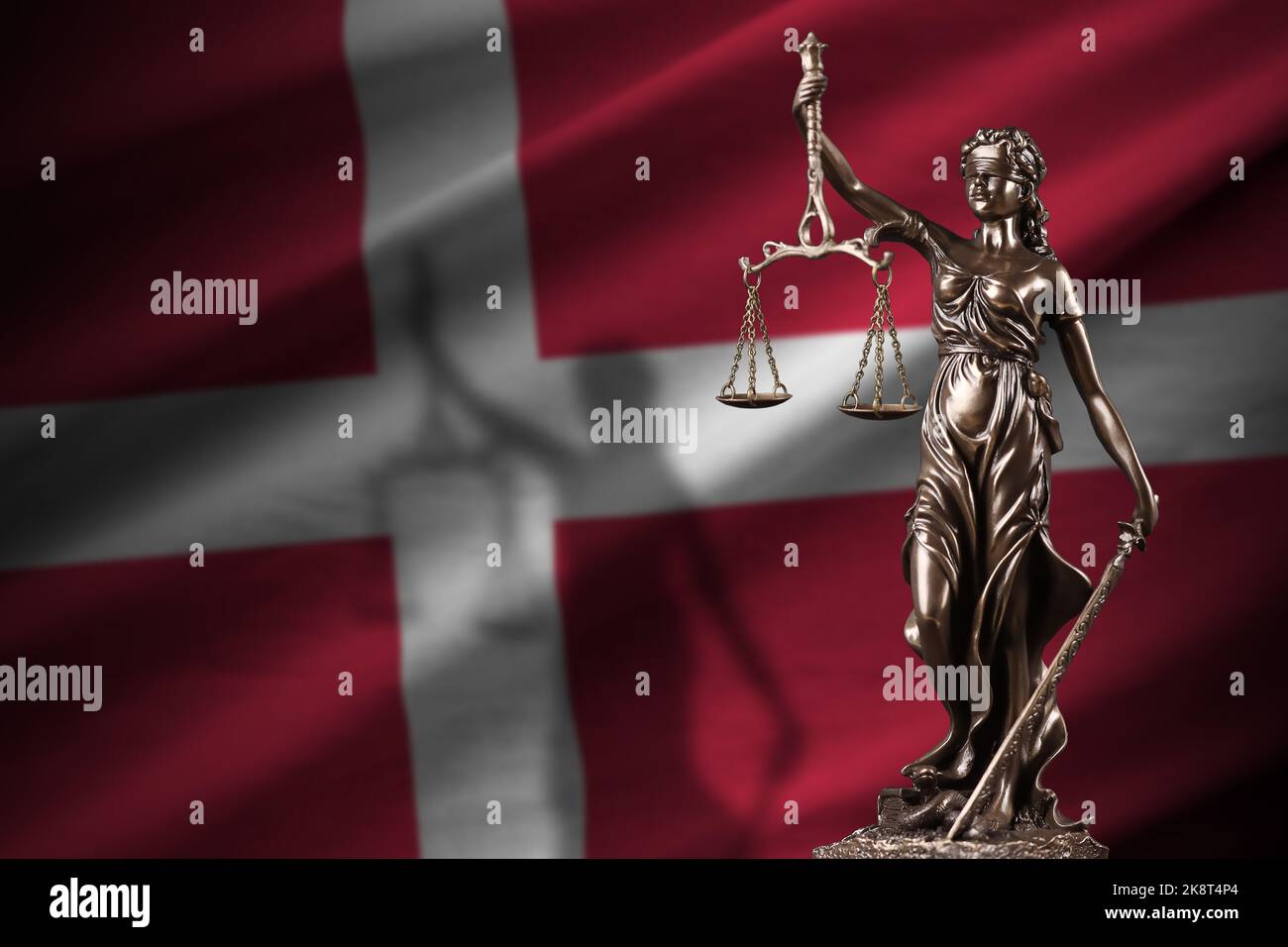 Denmark flag with statue of lady justice and judicial scales in dark ...