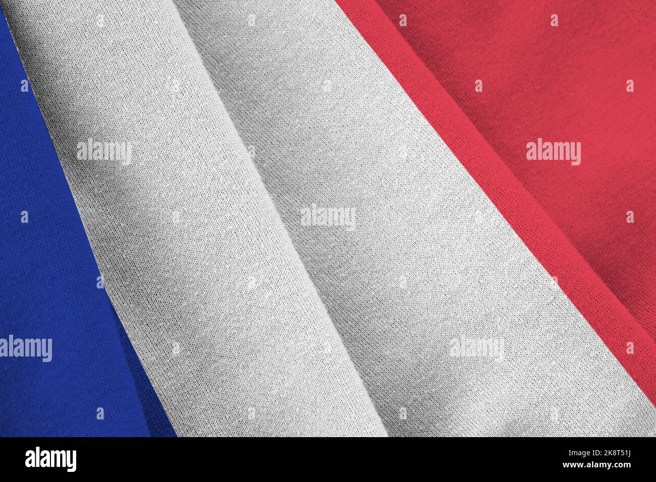 France flag with big folds waving close up under the studio light ...