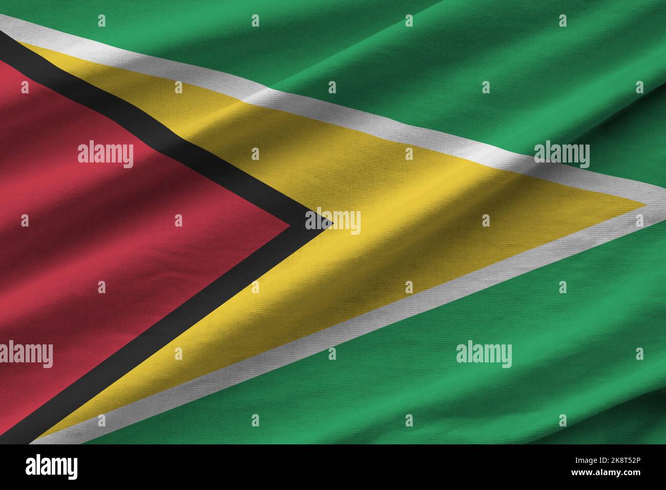 Guyana flag with big folds waving close up under the studio light indoors. The official symbols ...