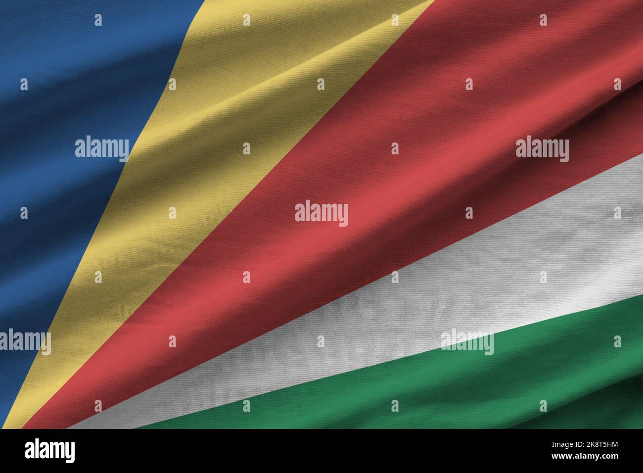 Seychelles flag with big folds waving close up under the studio light ...