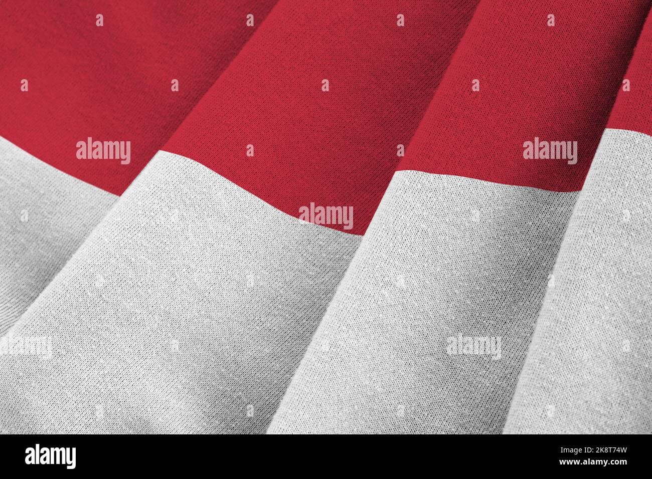 Monaco flag with big folds waving close up under the studio light ...