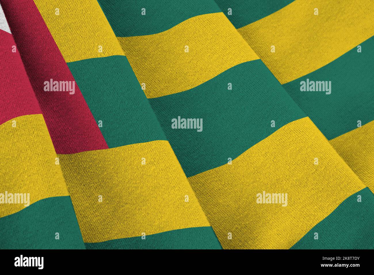 Togo flag with big folds waving close up under the studio light indoors ...