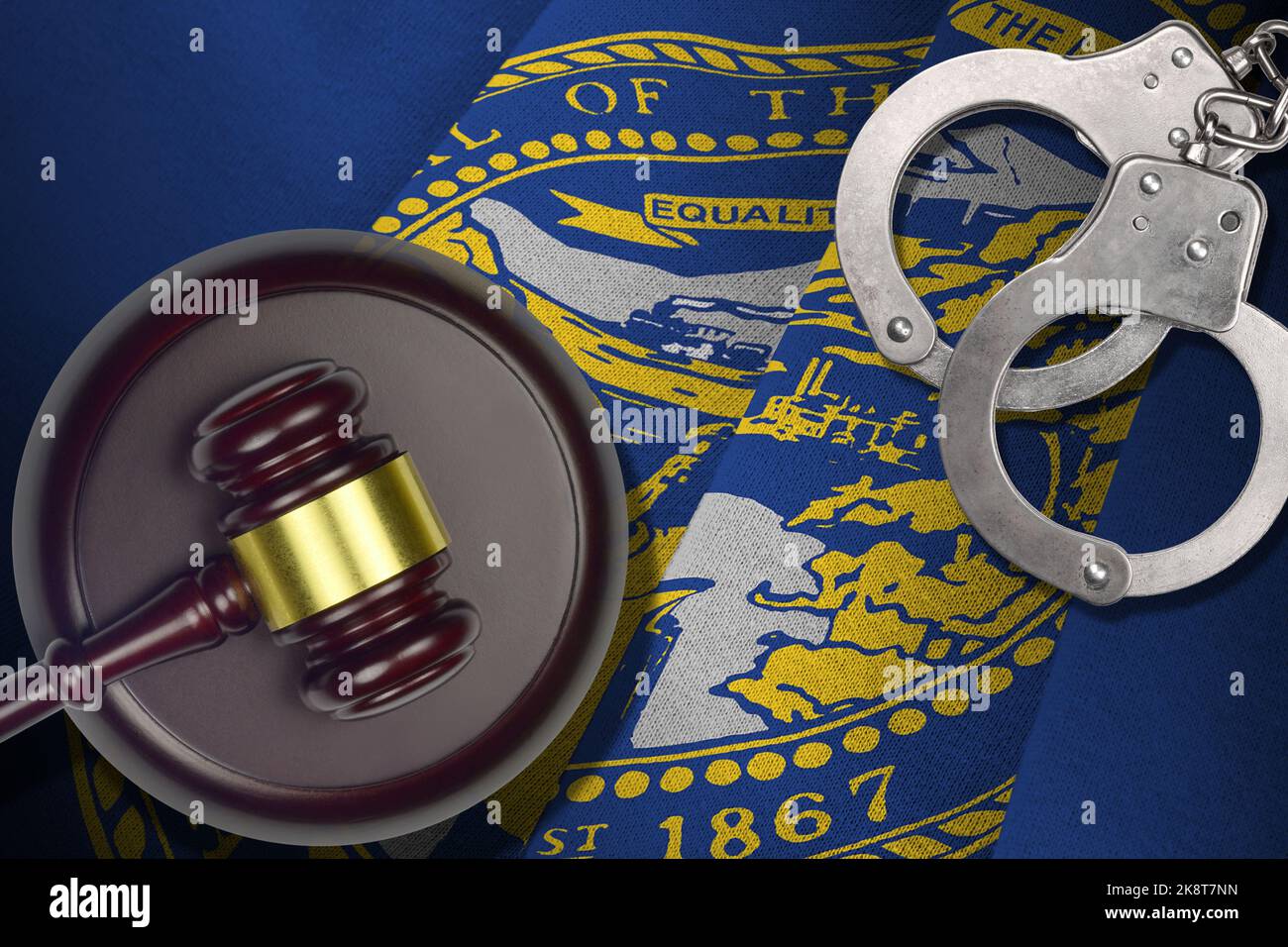 Nebraska US state flag with judge mallet and handcuffs in dark room ...