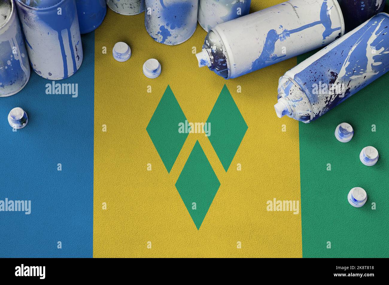 Saint Vincent and the Grenadines flag and few used aerosol spray cans ...