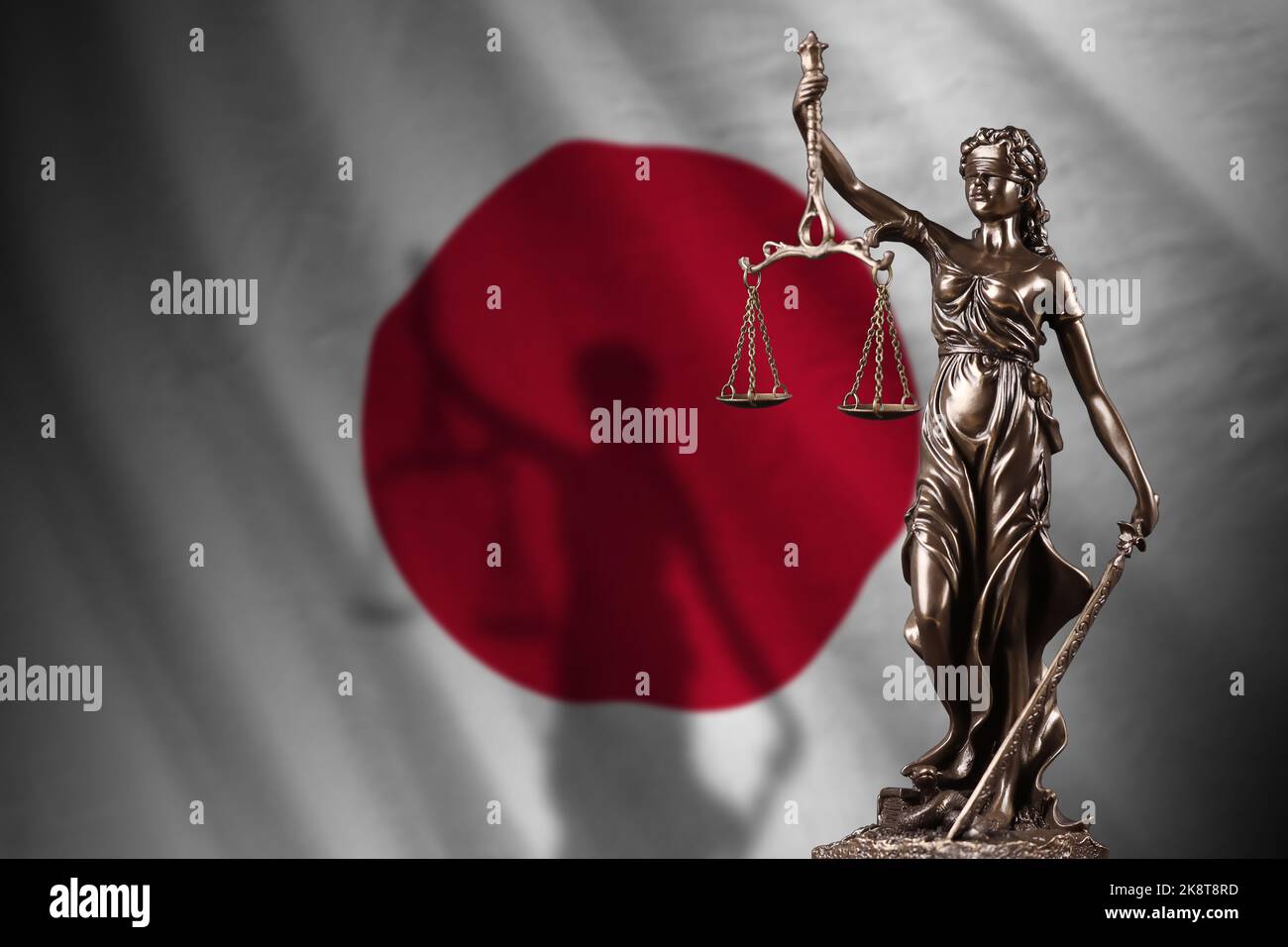 Japan flag with statue of lady justice and judicial scales in dark room ...