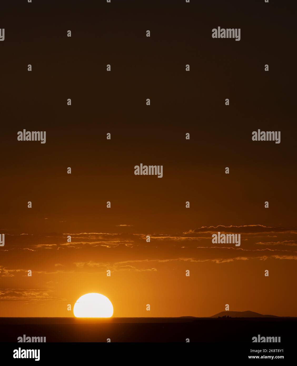 A breathtaking view of bright dawning sun in dark orange sunset sky ...