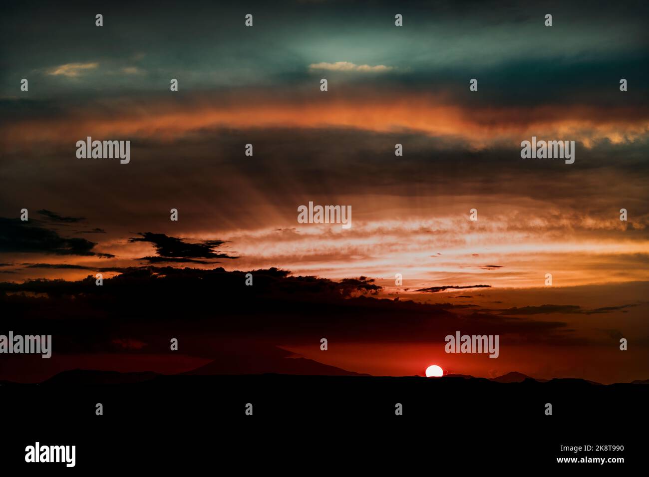 Beautiful sunset cloudscape with small sun and dark pink clouds in sky ...