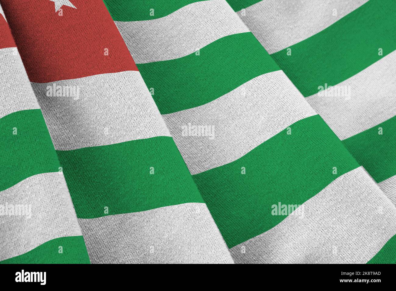 Abkhazia flag with big folds waving close up under the studio light ...