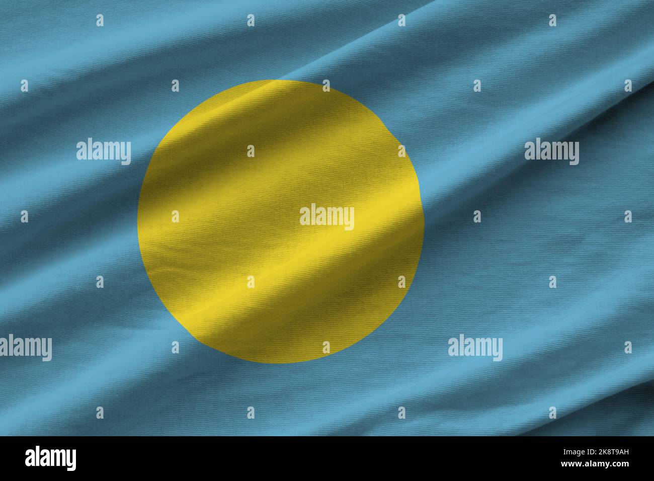 Palau flag with big folds waving close up under the studio light ...