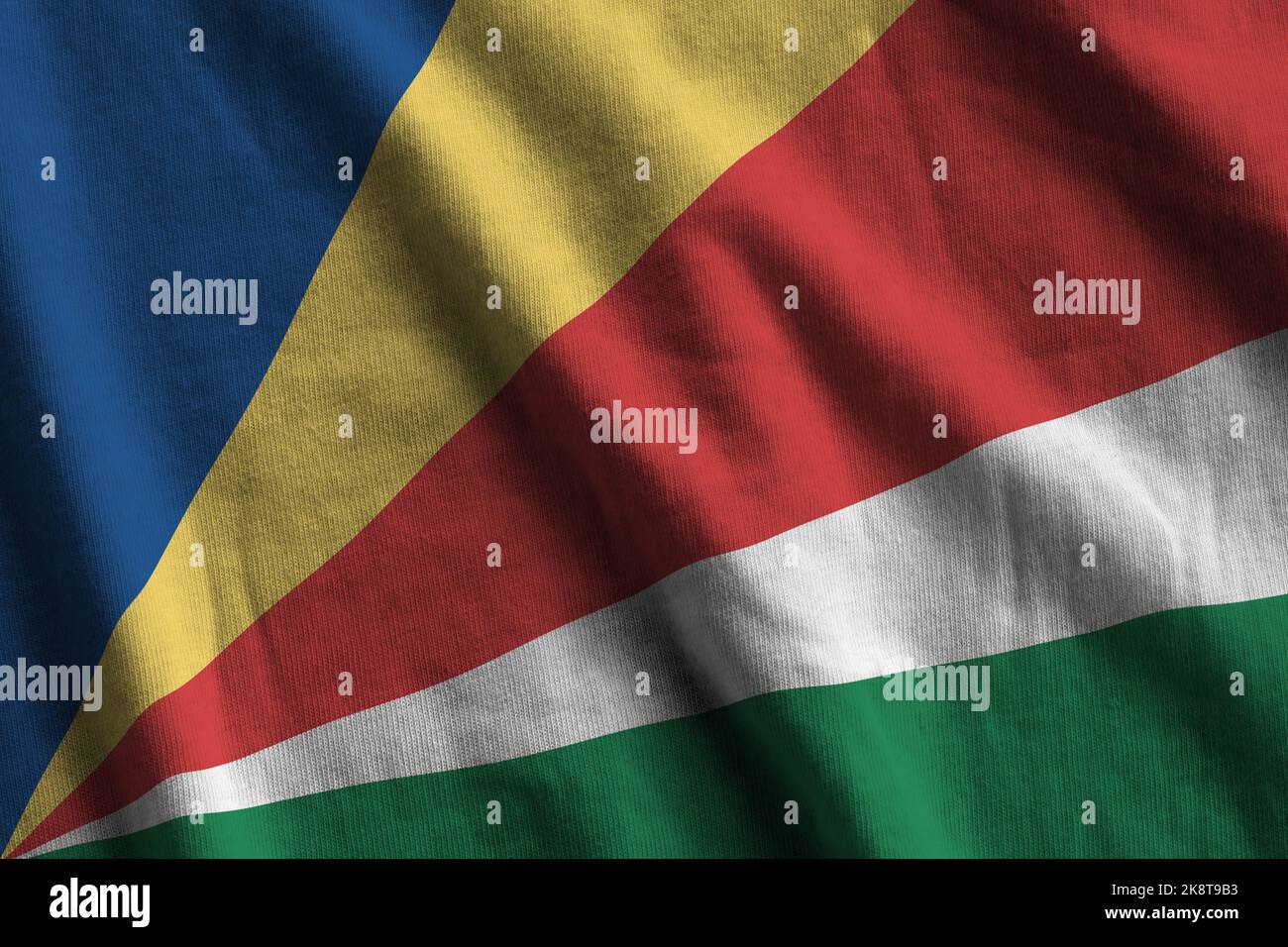 Seychelles flag with big folds waving close up under the studio light ...