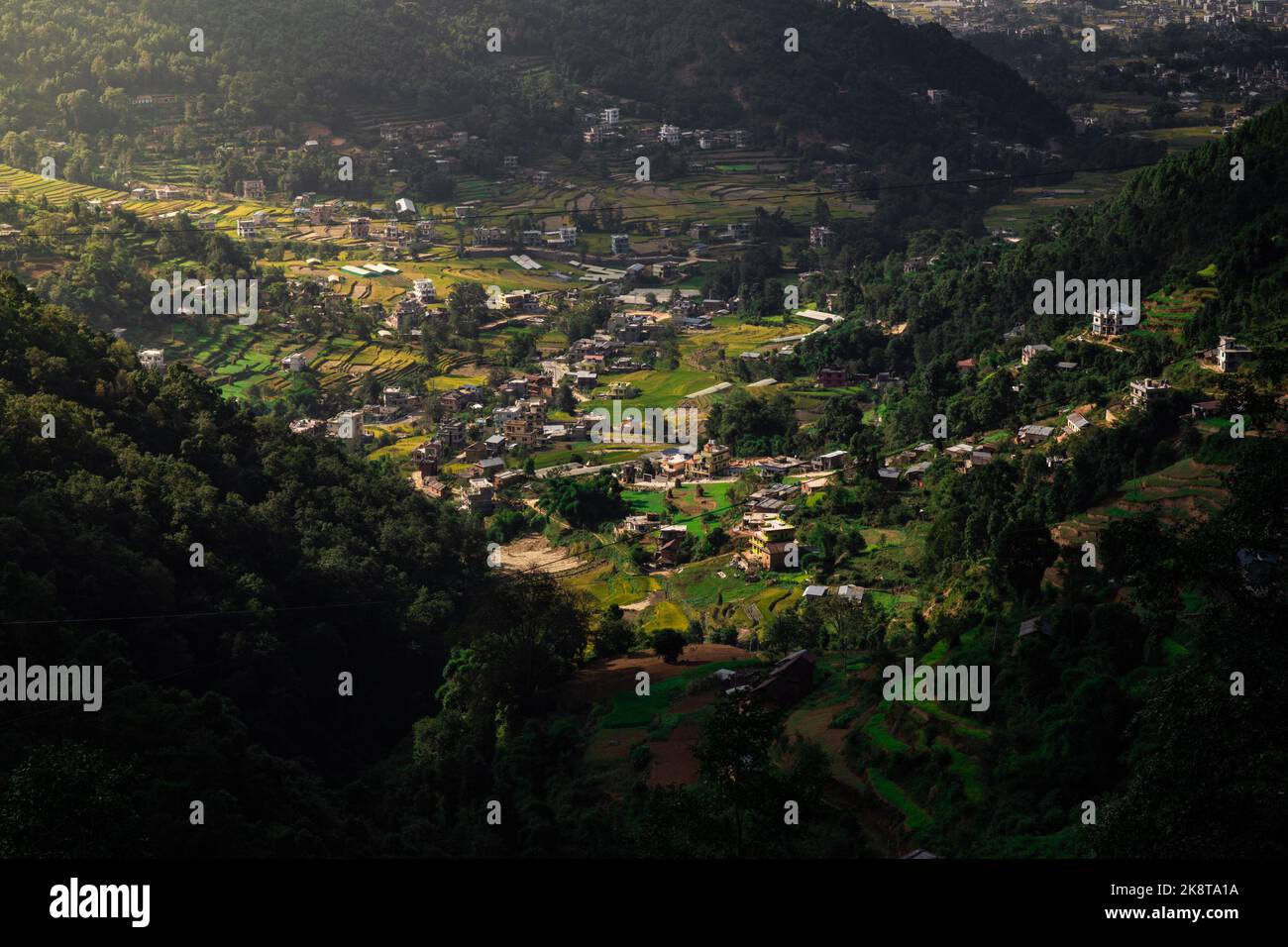 An aerial of a small village in a green valley surrounded by hills and ...