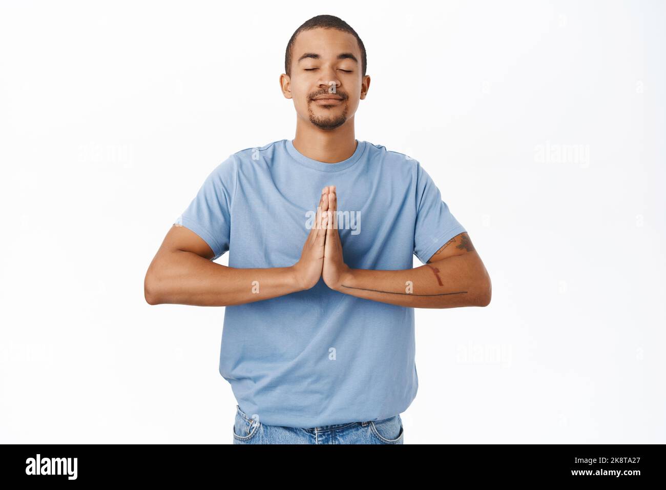 Namaste. Mindful young man meditating, holding hands in pray and ...