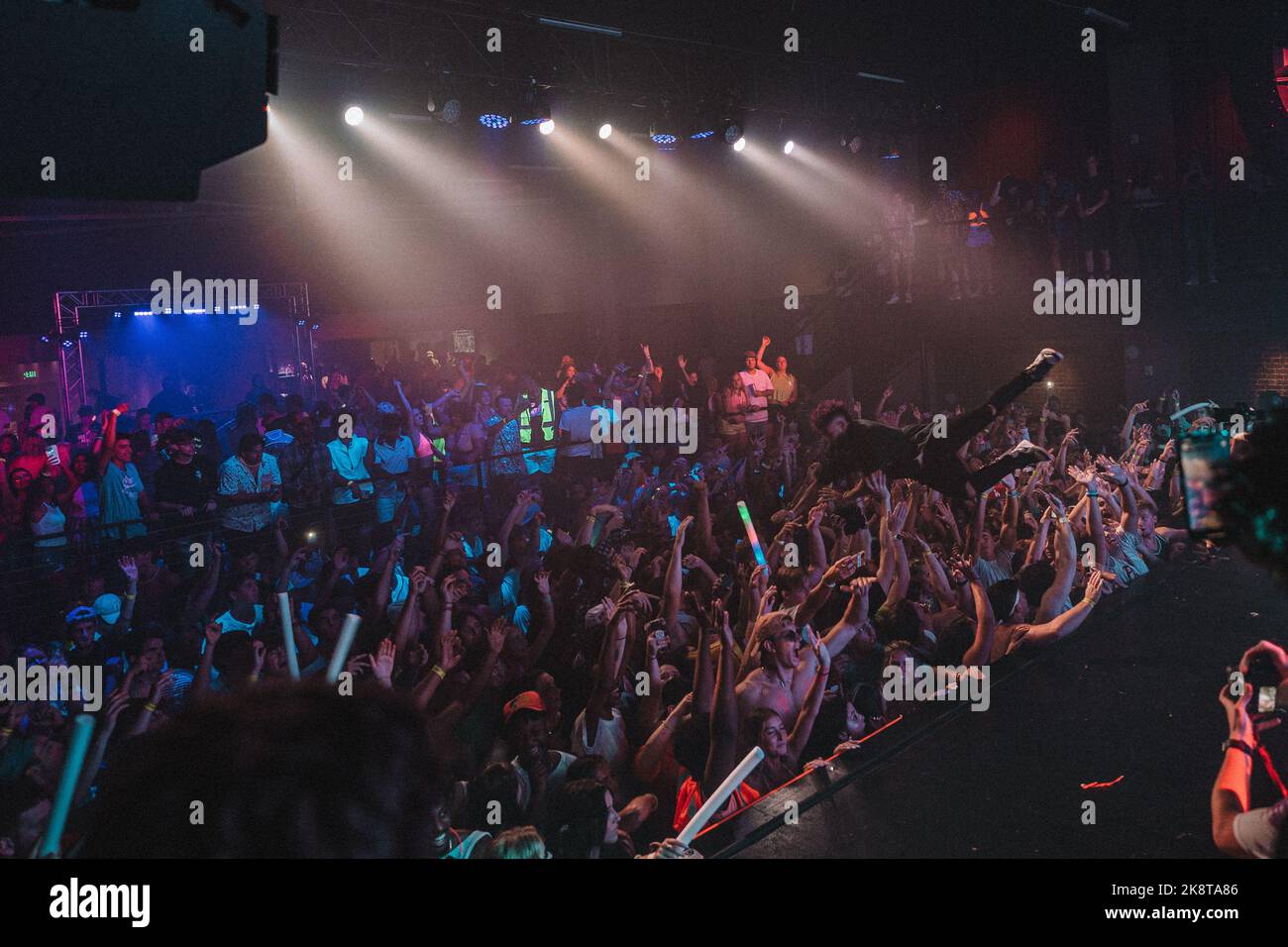A DJ jumping into the crowd during music festival with bright lights in ...