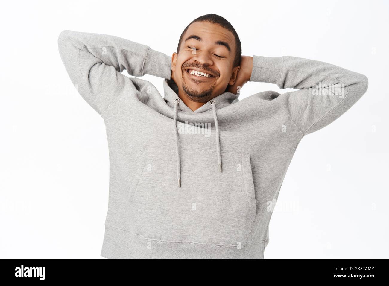 Lazy and happy young man resting, holding hands behind head and smiling ...