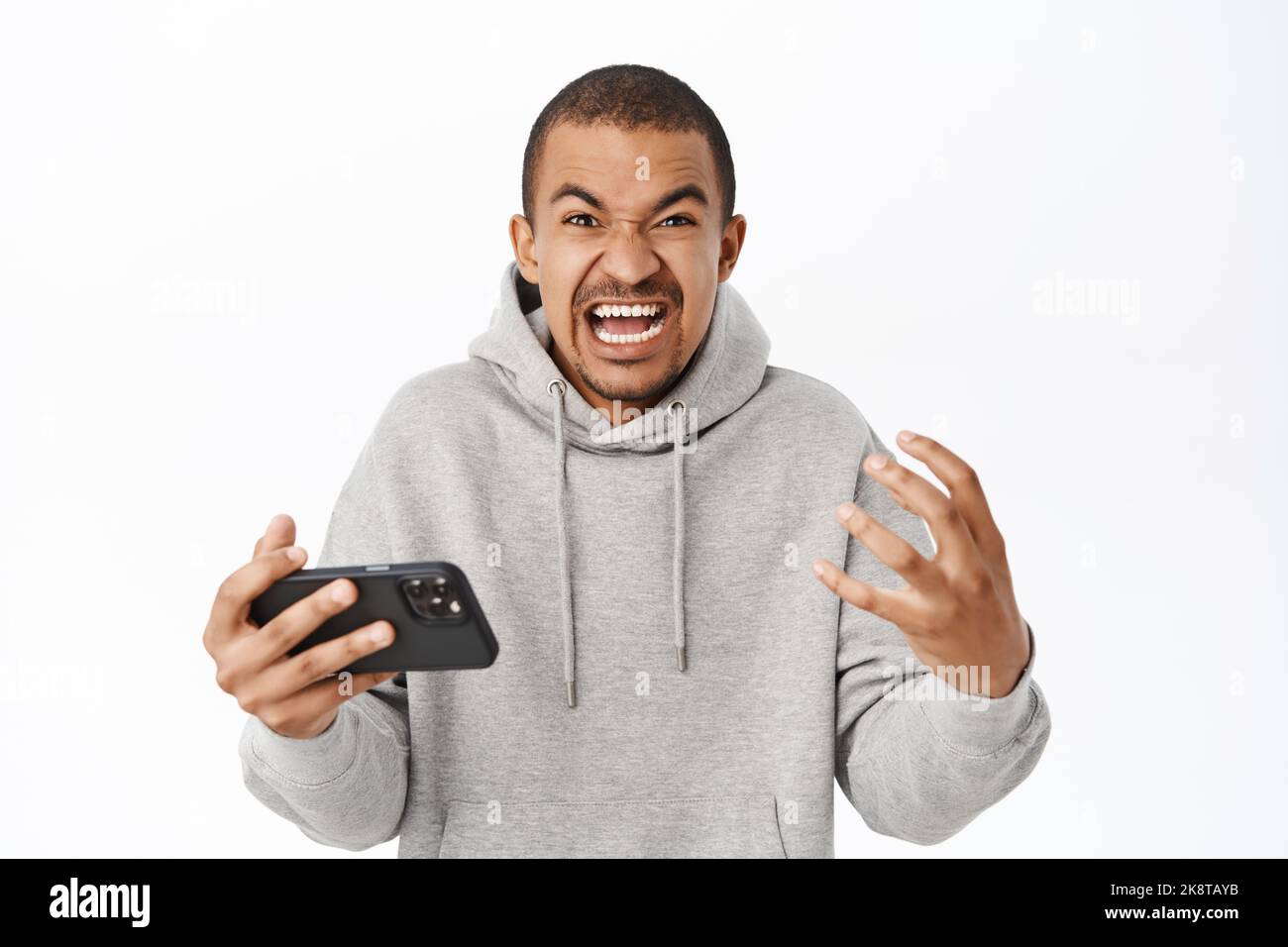 Angry man react to smth on smartphone, shouting and shaking furious ...