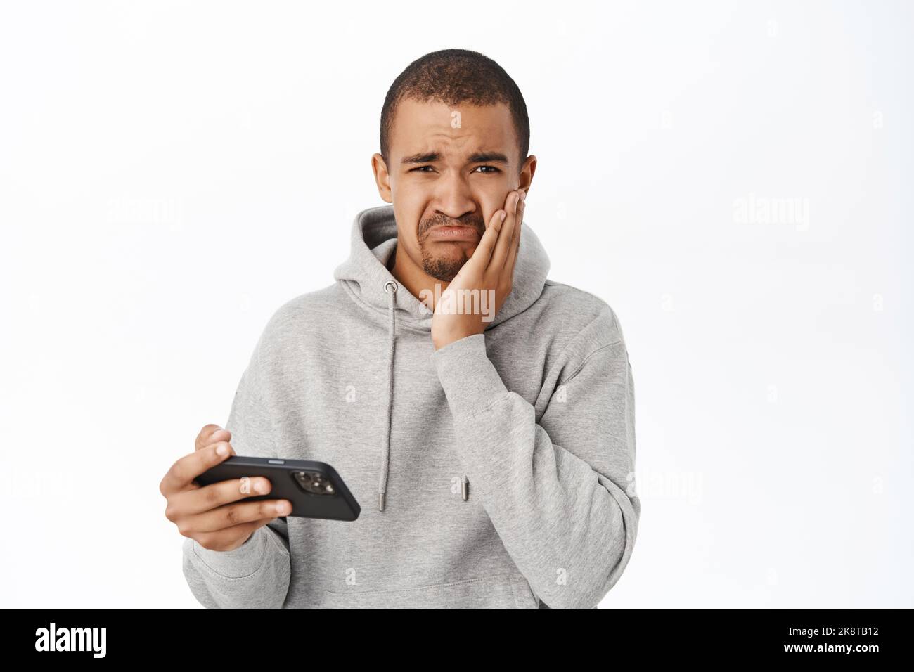 Crying man watching smth sad on mobile phone, looking gloomy, standing ...