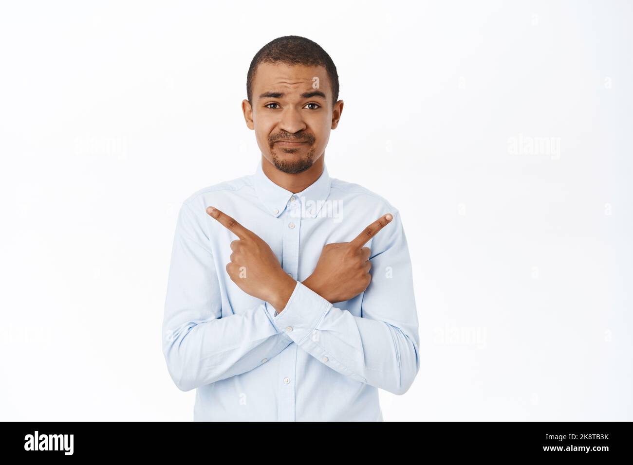 Portrait of confused office worker, young man pointing sideways, cannot ...