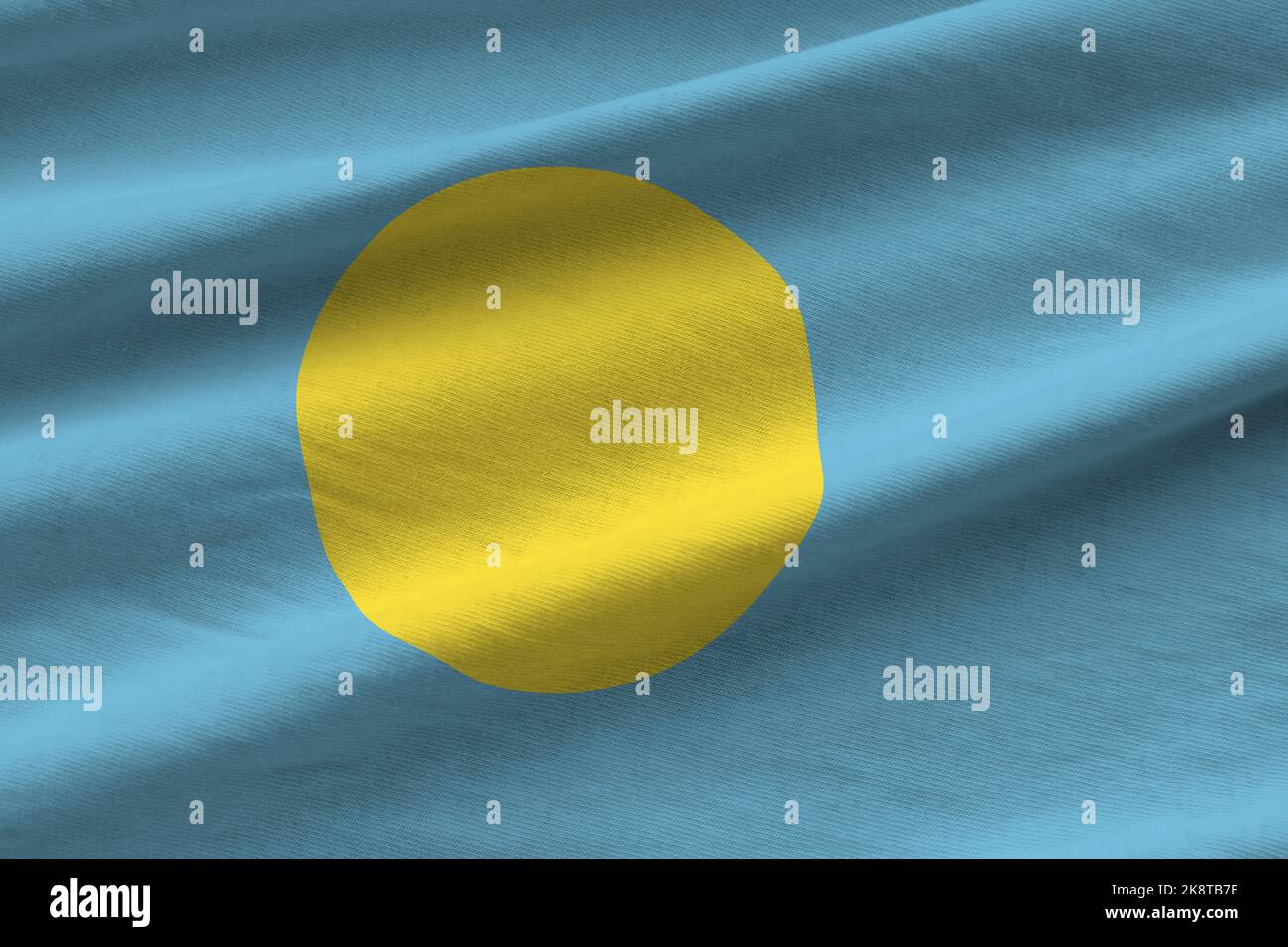 Palau flag with big folds waving close up under the studio light ...