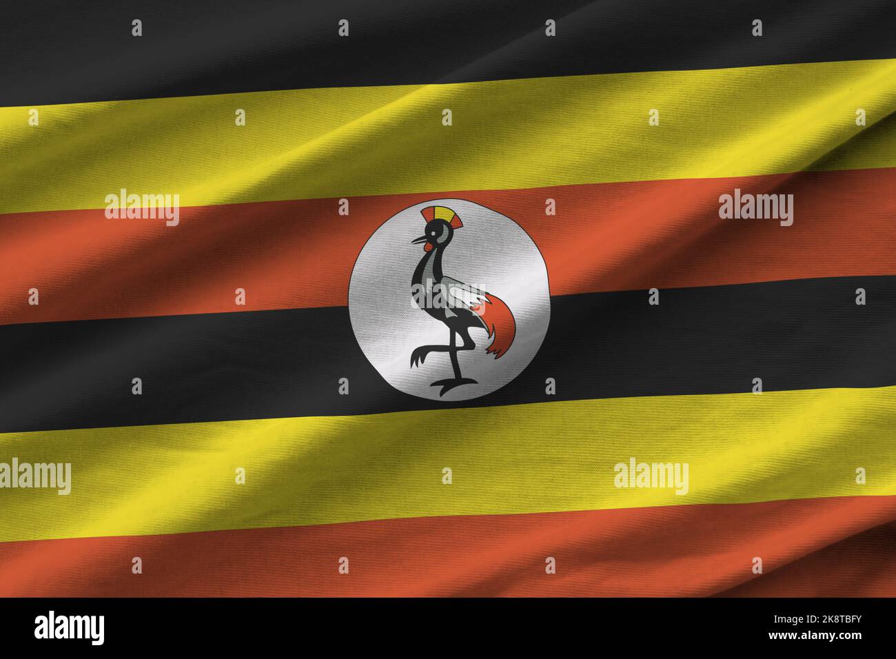 Uganda flag with big folds waving close up under the studio light ...