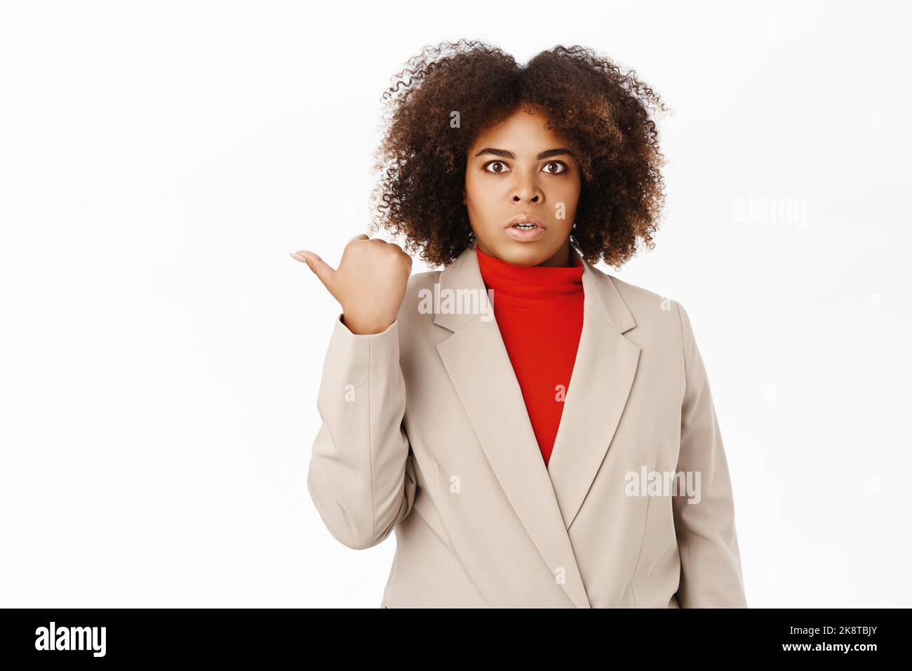Shocked black businesswoman, pointing left, looking startled and ...