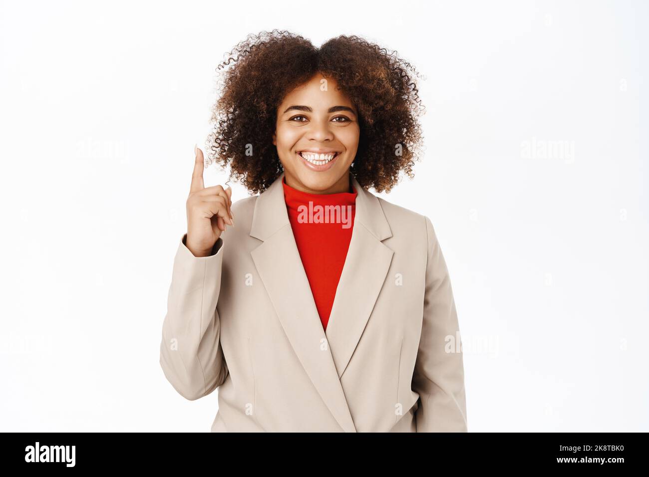 Smiling businesswoman, black woman, pointing finger up, shows direction ...