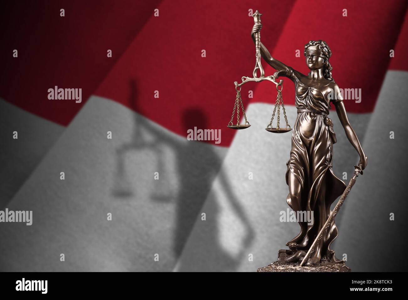 Monaco flag with statue of lady justice and judicial scales in dark ...