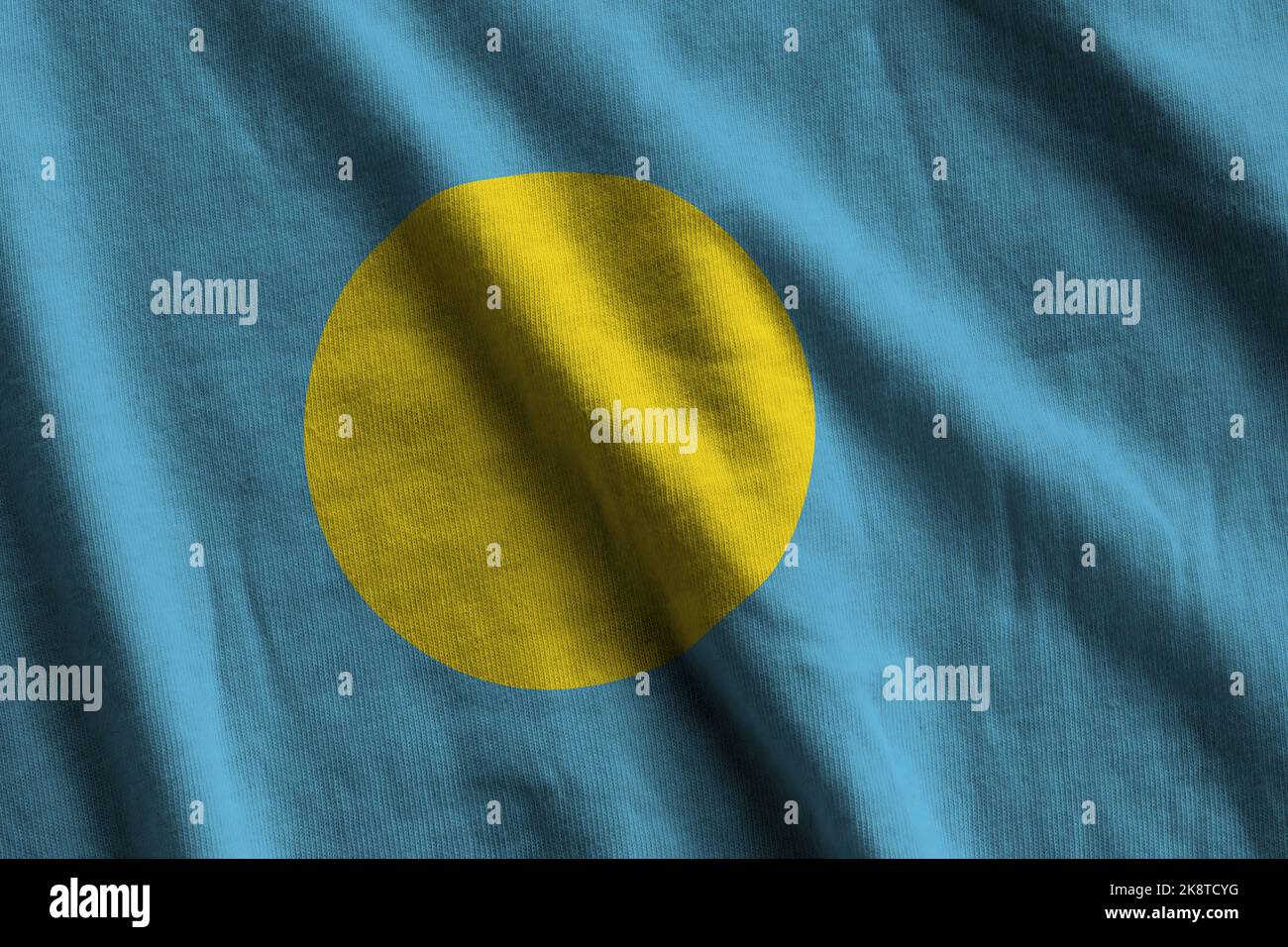 Palau flag with big folds waving close up under the studio light ...