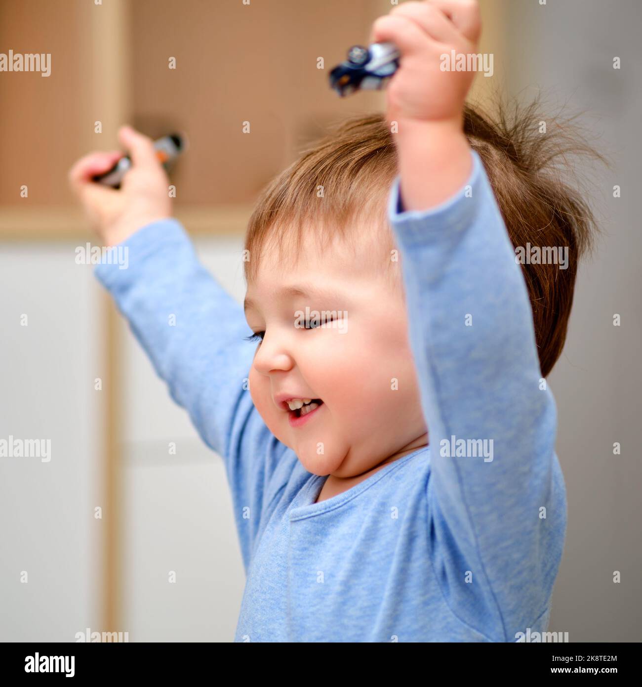 Portrait of a happy toddler baby boy with his hands up. The face of a ...