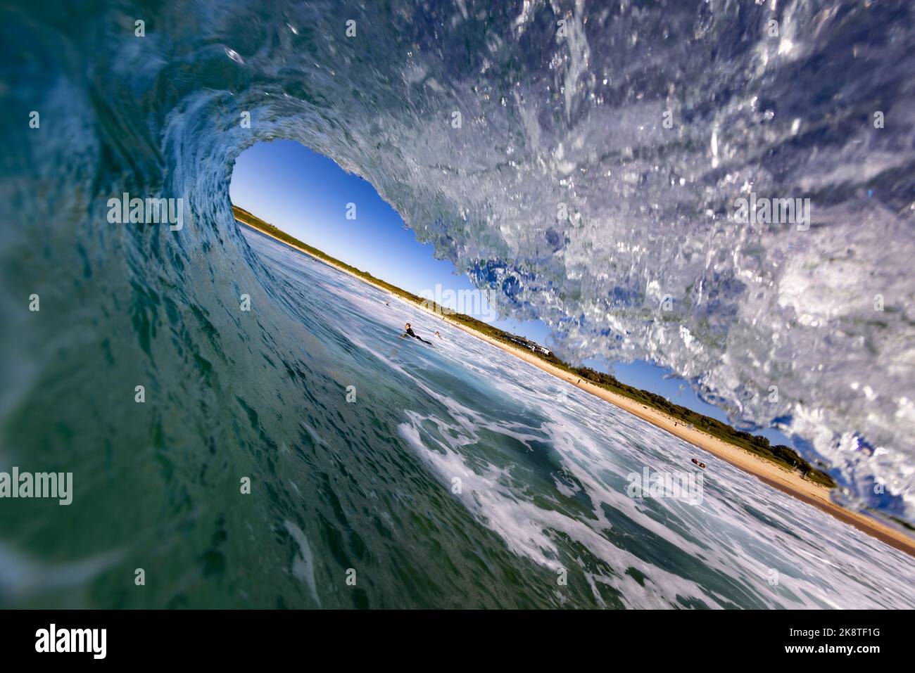 A closeup of a wave tunnel in the ocean with a person surfing and the ...